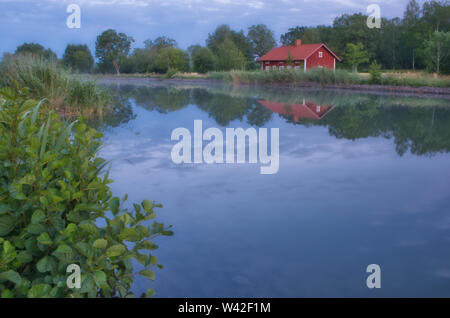 red cottage on a canal in the background and green plants in the ...