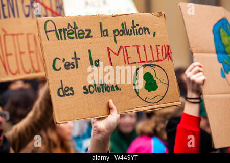 A closeup view of a cardboard French poster, saying save the earth more ...