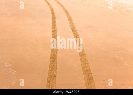 Vehicle machine tracks imprints on beach sand though the frame overhead ...