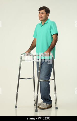 Old handicapped man with a walker standing against white background ...