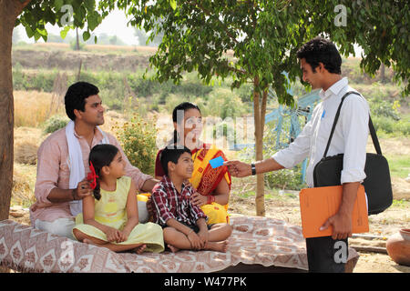 Executive giving bank card to rural family Stock Photo - Alamy