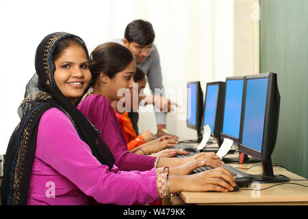 Women using computers with teacher assistance Stock Photo - Alamy