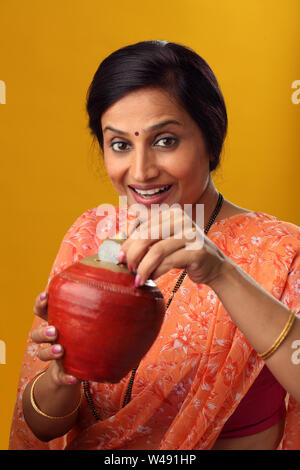 Mature woman putting coin in piggy bank on blue background Stock Photo ...