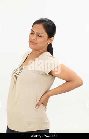 Stressful woman suffering from lower back pain blue background Stock ...