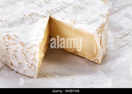 sliced round brie cheese head with white mold on white paper Stock ...