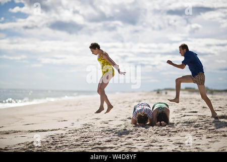 Friends playing leapfrog on the beach Stock Photo - Alamy