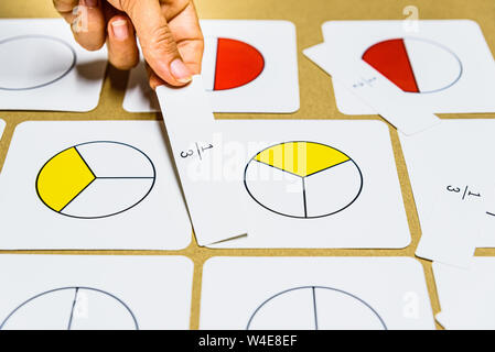 Hand of teacher montessori guide graphically shows fractions with ...