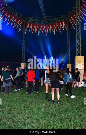 Teenagers listening to rave music in a big marque at an outdoor music ...