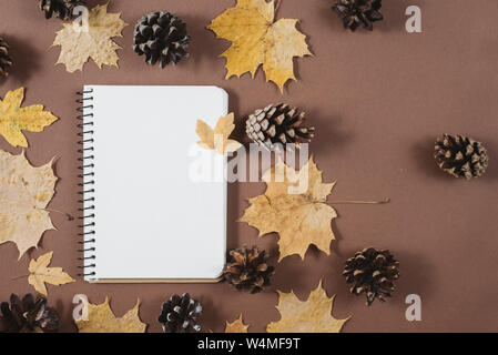 Autumn leaves pattern with bumps and notebook on brown background ...