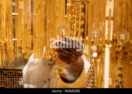 A dealer takes a chain from the display of his shop in the Gold-suq of ...