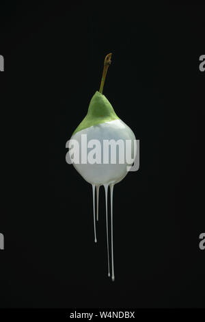 Green Pear dripping white paint on a black background Stock Photo - Alamy