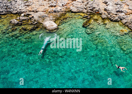 Aerial view of swimmiers and snorkellers in a hot, crystal clear ocean ...