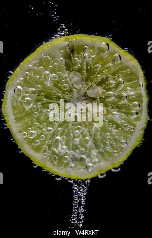 Underwater lemon slice in soda water or lemonade with bubbles. Refreshing soda tonic fizzy ...