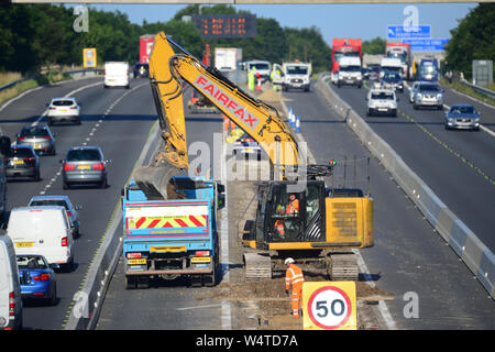 digger working in central reservation loading lorry's with rubble ...