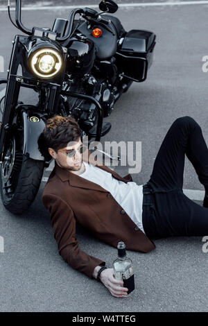 Motorcyclist in jacket lying on his motorcycle in the countryside ...