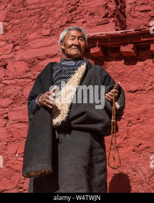 Portrait of a tibetan man wearing a coat with very long sleeves to ...