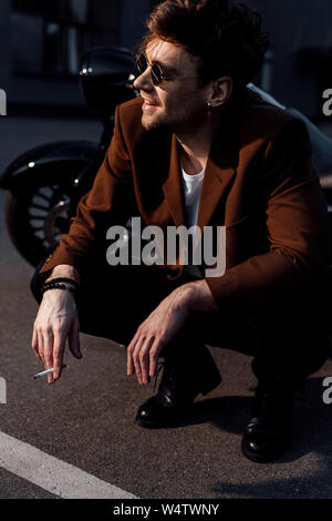 Man squatting and smoking a cigarette. Smoking bad boy against old ...