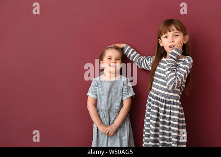 Emotional little child measuring her height near black wall indoors ...