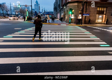 A pedestrian walks across a zebra crossing illuminated by LED lights in ...