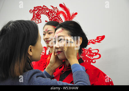 Chinese craftswoman Liang Ying helps a model finish make-up after ...