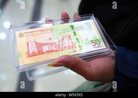 A local Chinese resident shows commemorative coins for the 70th ...