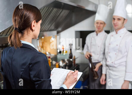 Male restaurant manager briefing to his kitchen staff in the commercial ...