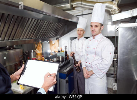 Male restaurant manager briefing to his kitchen staff in the commercial ...