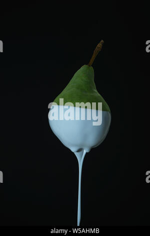 Beautiful fresh pear dripping white paint on a black background ...