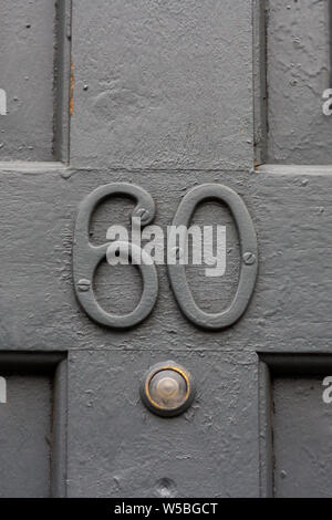 House number 60 with the sixty painted in grey on a grey wooden front ...