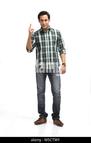 Confident casual man pointing upward while wearing shirt, standing on ...