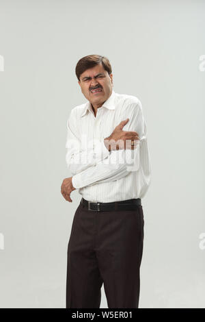 Indian businessman suffering from arm pain Stock Photo - Alamy