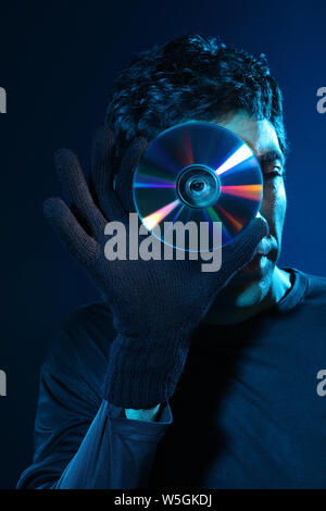 Hacker holding a pirated compact disc in front of face Stock Photo - Alamy