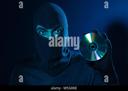 Hacker holding a pirated compact disc Stock Photo - Alamy