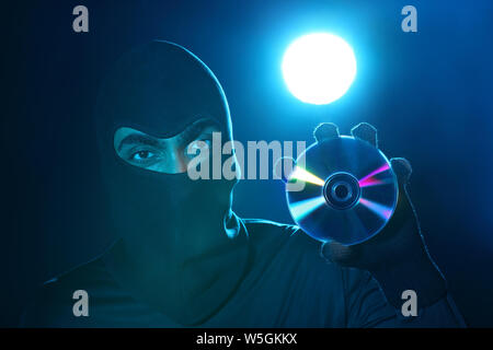 Hacker holding a pirated compact disc Stock Photo - Alamy
