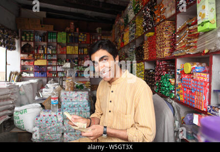 Shopkeeper counting money in grocery shop Stock Photo - Alamy