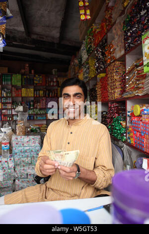Shopkeeper counting money in grocery shop Stock Photo - Alamy