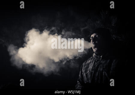 adult man smoking at night making a big smoke effect in back light ...