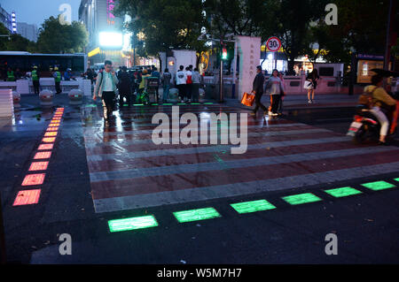 Pedestrians walk on a smart zebra crossing backed by automatic sensors ...