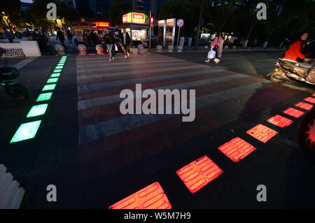 Pedestrians walk on a smart zebra crossing backed by automatic sensors ...