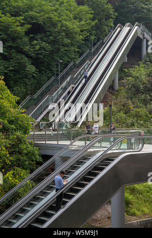 Local residents take the newly-built escalators to reach the top of a ...