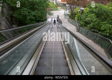 Local residents take the newly-built escalators to reach the top of a ...