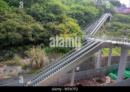Local residents take the newly-built escalators to reach the top of a ...