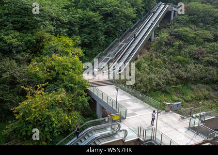 Local residents take the newly-built escalators to reach the top of a ...