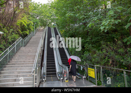 Local residents take the newly-built escalators to reach the top of a ...