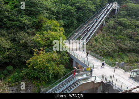 Local residents take the newly-built escalators to reach the top of a ...