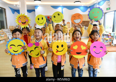 Smiley young Chinese kids show smiling cartoon faces they made to ...