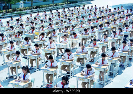 Chinese primary school students sit in rows as they practice ...