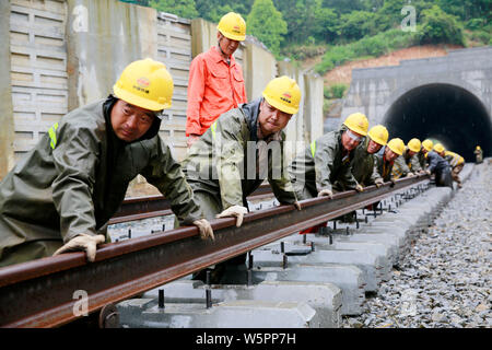 Chinese construction workers lay rails on crossties or railroad ...