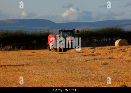 A modern straw compactor collecting the straw and rolling it into huge ...