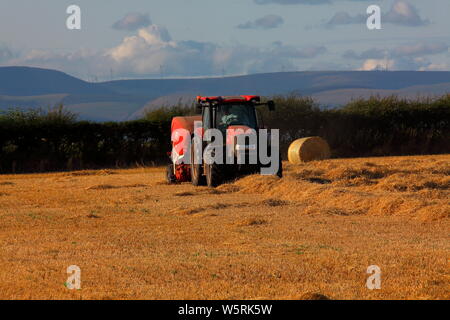 A modern straw compactor collecting the straw and rolling it into huge ...